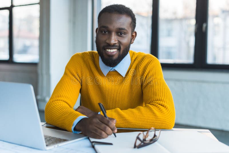 Smiling African American Businessman Holding Pen and Looking at Camera ... Smiling African American Businessman Holding Pen and Looking at Camera ...