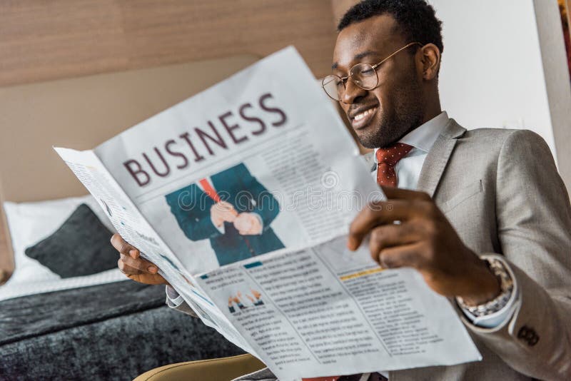 Smiling African American Businessman in Suit Reading Business Newspaper ... Smiling African American Businessman in Suit Reading Business Newspaper ...