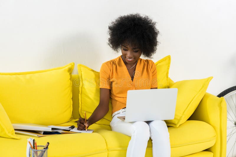 Smiling African American Female Freelancer with Laptop Making Notes ... Smiling African American Female Freelancer with Laptop Making Notes ...