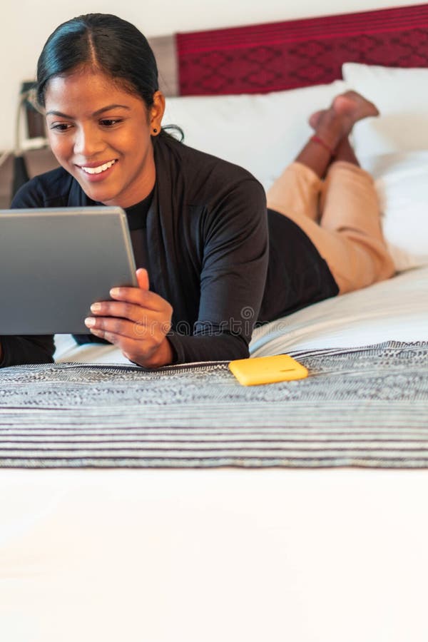 Smiling African-American Woman Lying in Bed Using a Digital Tablet and ...