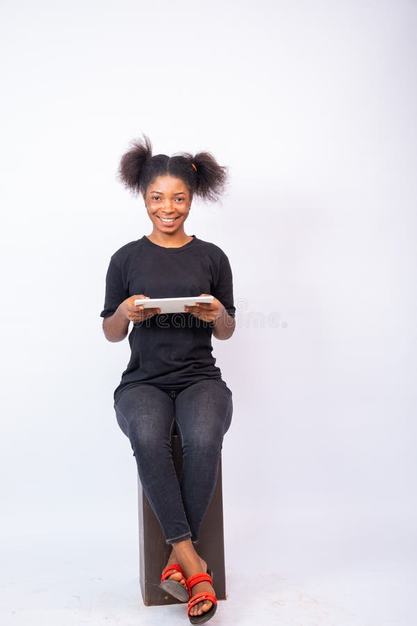 Smiling African Lady Using a Tablet Computer, Sitting Against a White ...