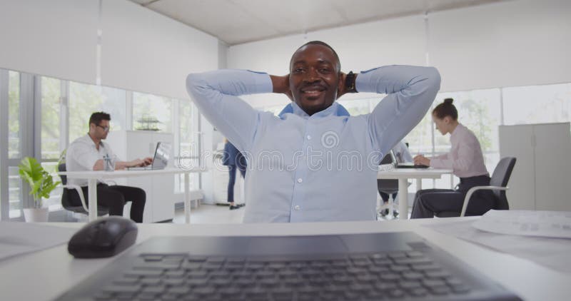 Smiling Afro-american Businessman Holding Hands Behind Head Sitting at ... Smiling Afro-american Businessman Holding Hands Behind Head Sitting at ...