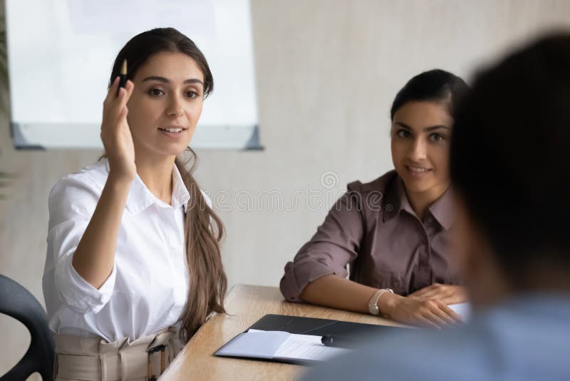 Businesswoman Raising Hand Asking Senior Coach Questions At Team Stock