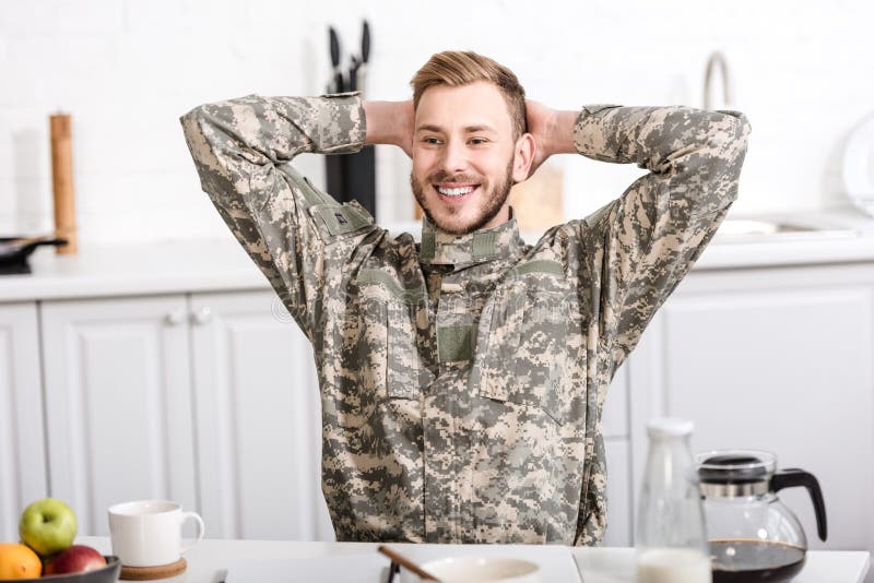 Smiling Army Soldier Sitting at Kitchen Table with Hands on Head and ...