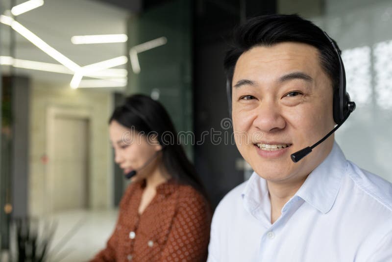 Smiling Asian Business Professionals Using Headsets during an Office ...