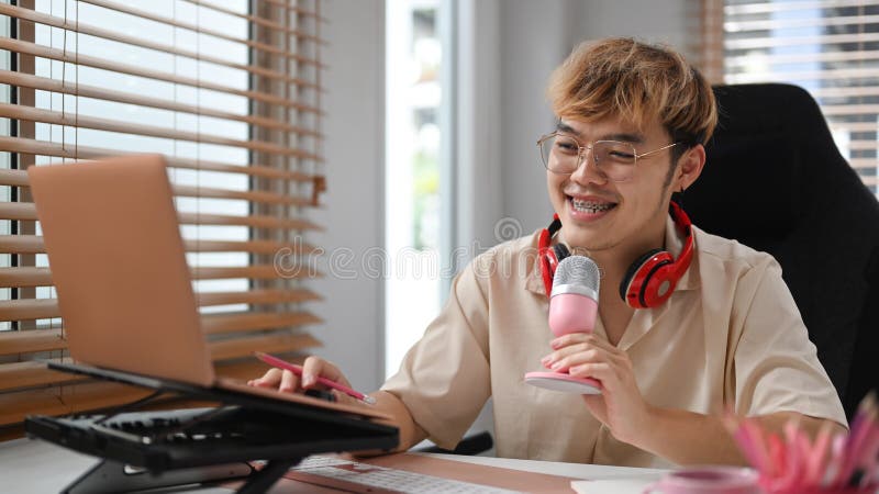 Smiling Asian Male Using Microphone and Laptop Computer Streaming from ...