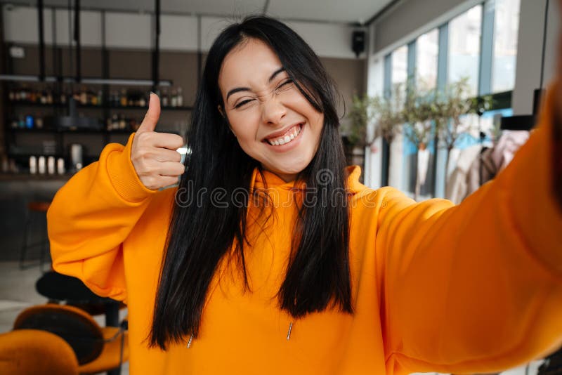 Smiling Asian Woman Gesturing Thumb Up While Taking Selfie Photo Stock