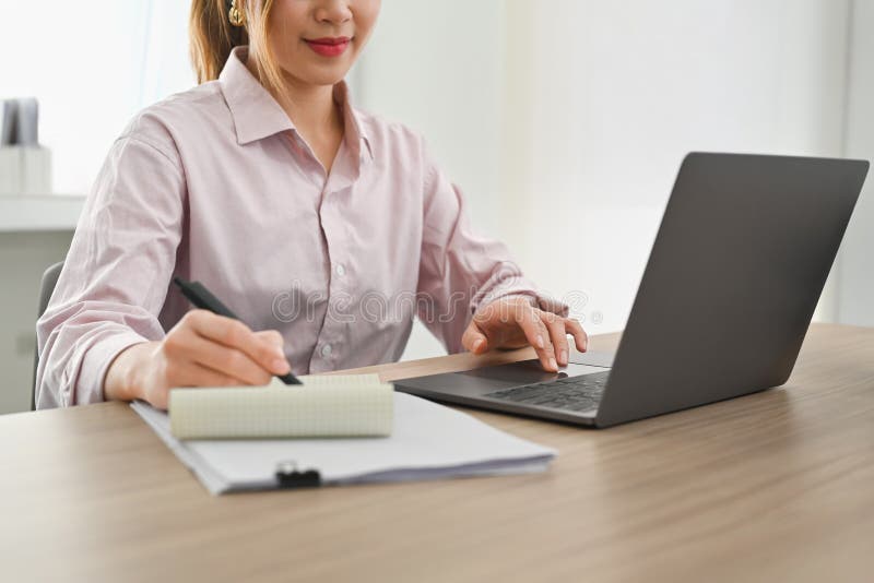 Smiling Asian Woman Worker Using Laptop Computer and Making Notes on ...