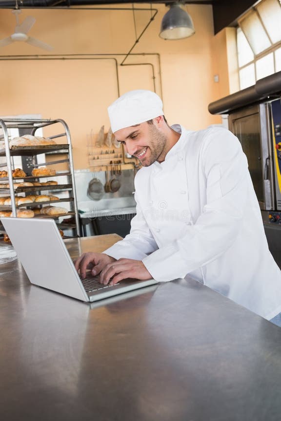 Smiling Baker Using Laptop on Worktop Stock Image - Image of building ...