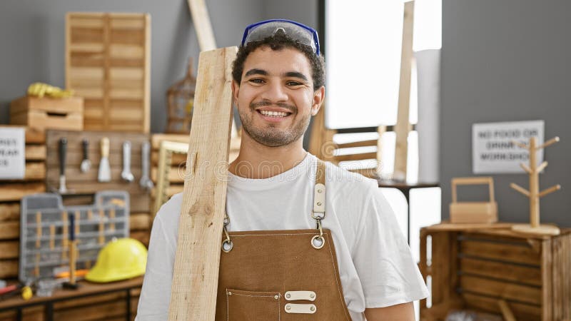 Smiling Bearded Man in Safety Goggles and Apron Holds Lumber in a ...