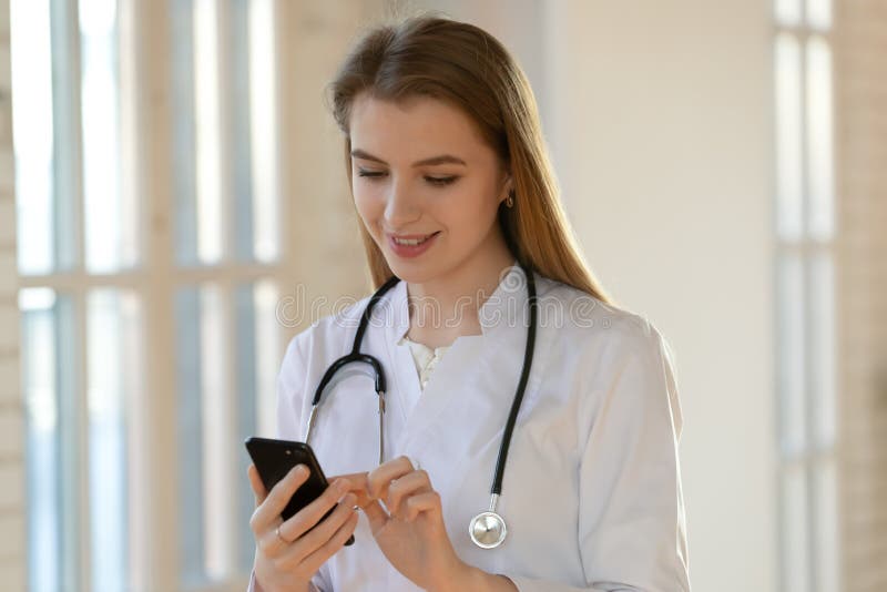 Smiling Beautiful Young General Practitioner Using Smartphone. Stock ...