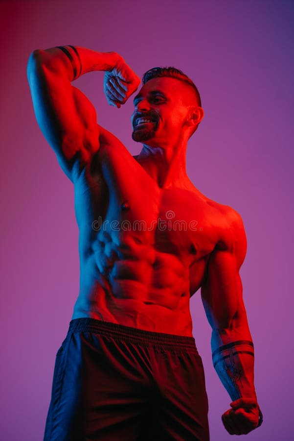 A Bodybuilder is Posing with a Flexed Bicep Under the Blue and Red ...