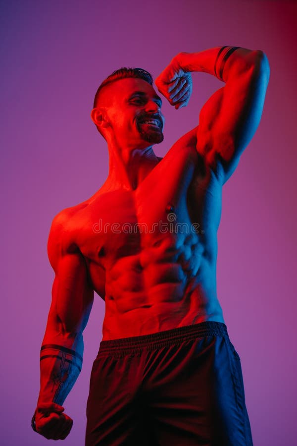 A Bodybuilder is Posing with a Flexed Bicep Under the Blue and Red ...