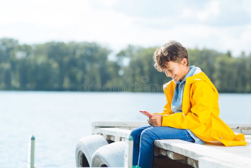 Smiling Boy Reading Message on Phone Sitting Near River Stock Image ...