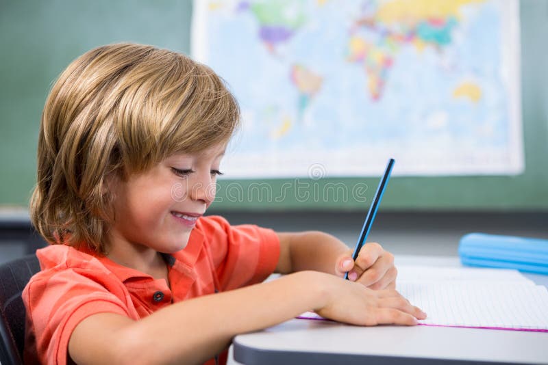 Smiling Boy Writing on Book in Classroom Stock Image - Image of ...