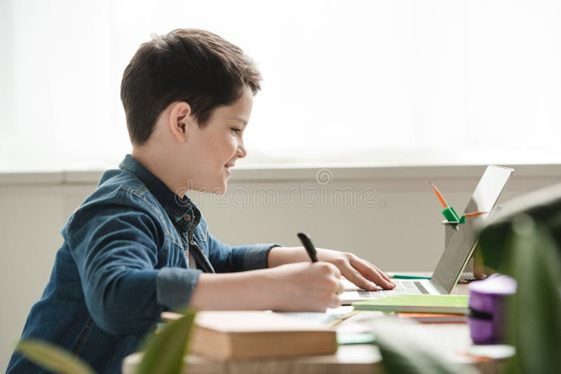 Boy Using Digital Tablet while Sitting at Desk Near Sister Writing in ...