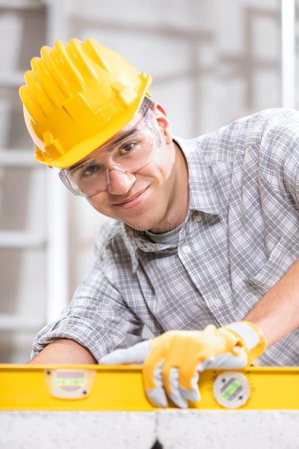 Smiling Builder in a Hardhat Using a Spirit Level Stock Photo - Image ...