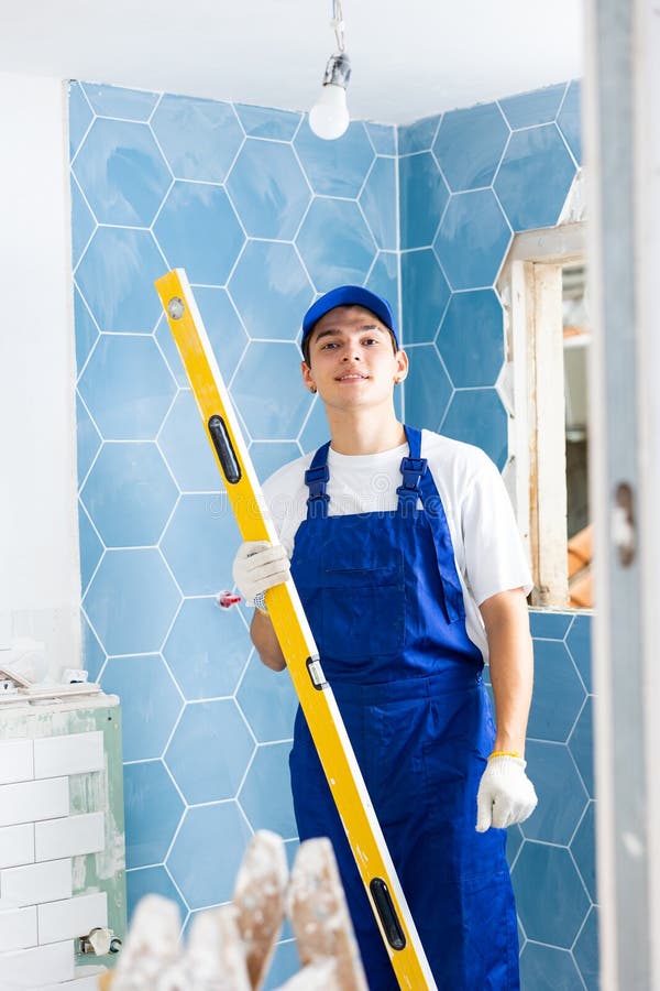 Smiling Builder Standing in Room Under Renovation with Level Meter ...