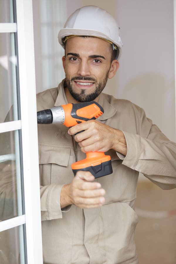 Smiling Builder Using Cordless Drill on Window Frame Stock Photo ...