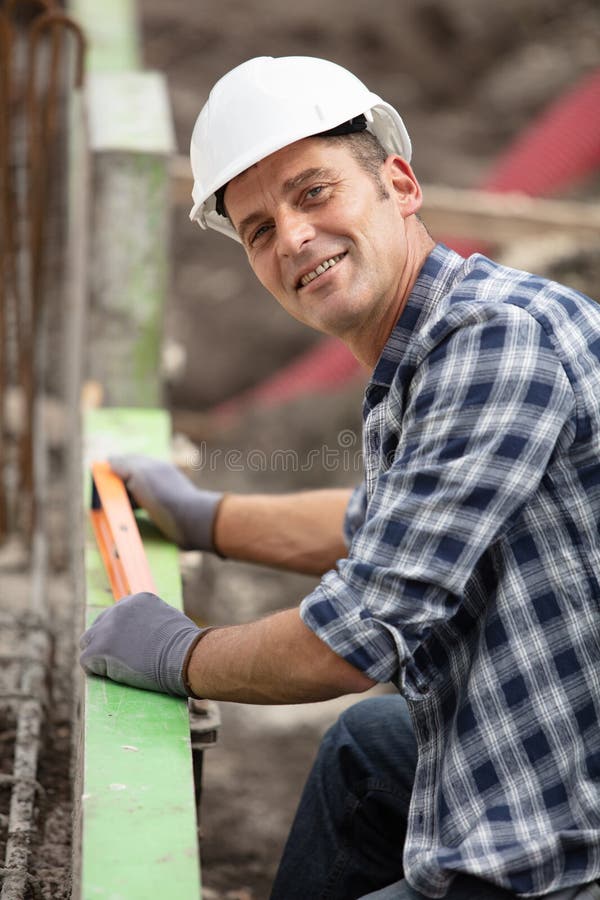 Smiling Builder Using Spirit Level on Construction Site Stock Photo ...
