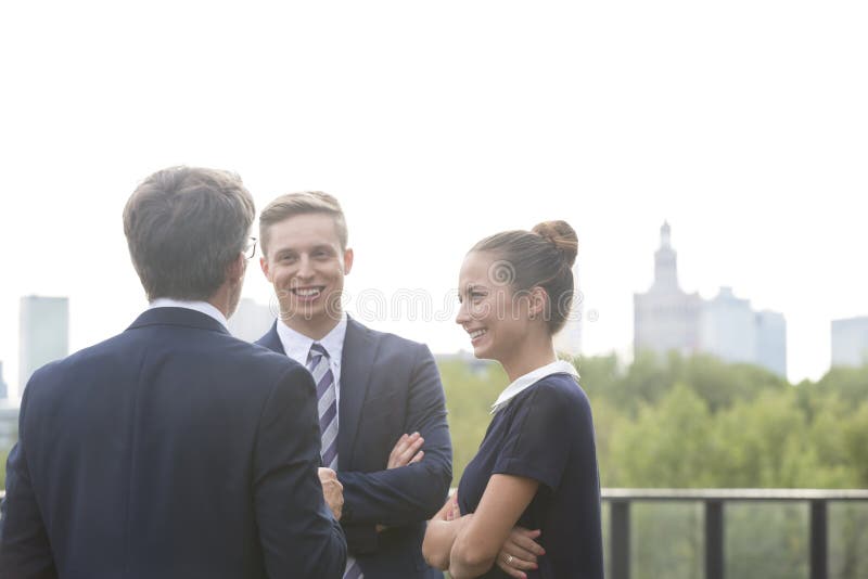 Smiling Business Colleagues Discussing while Standing in City Stock ... Smiling Business Colleagues Discussing while Standing in City Stock ...