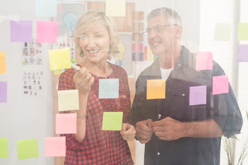 Smiling Business Team Pointing Post Its on the Wall Stock Image - Image ...