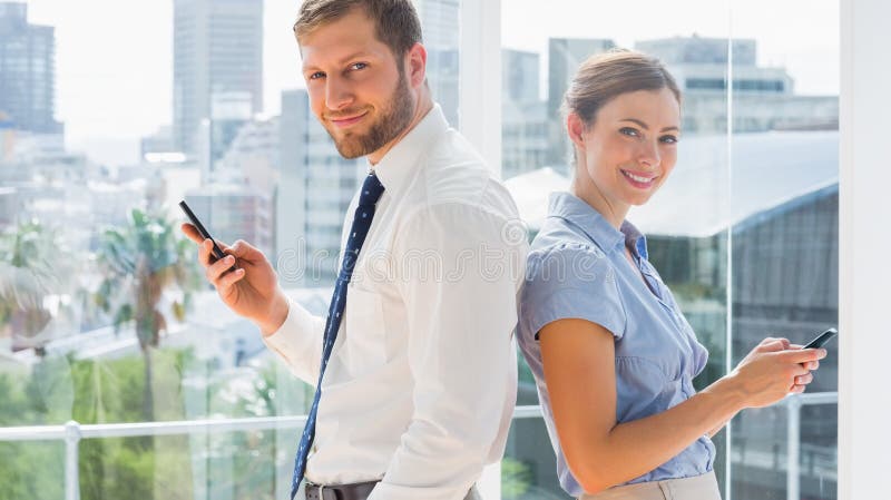Smiling Business Team Standing Back To Back and Texting Stock Photo ...