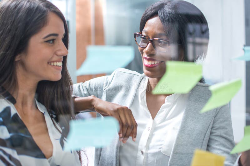 Smiling Business Women Discussing about Work Behind Glass with Sticky ...