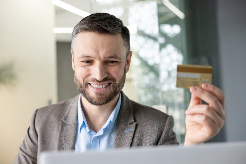 Smiling Businessman Working at Desk with Laptop and Documents in Modern ...