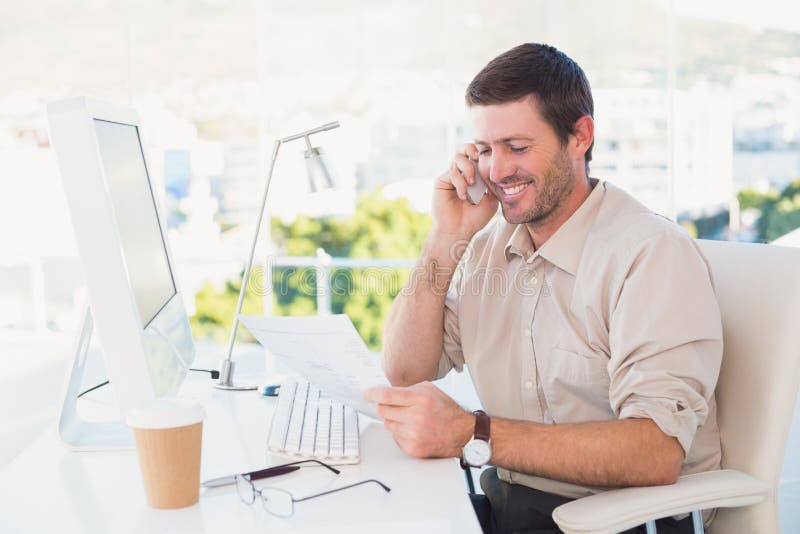 Smiling Businessman Making a Call and Reading a Document Stock Image ...