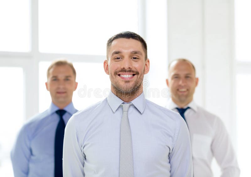 Smiling Businessman in Office with Team on Back Stock Photo - Image of ...