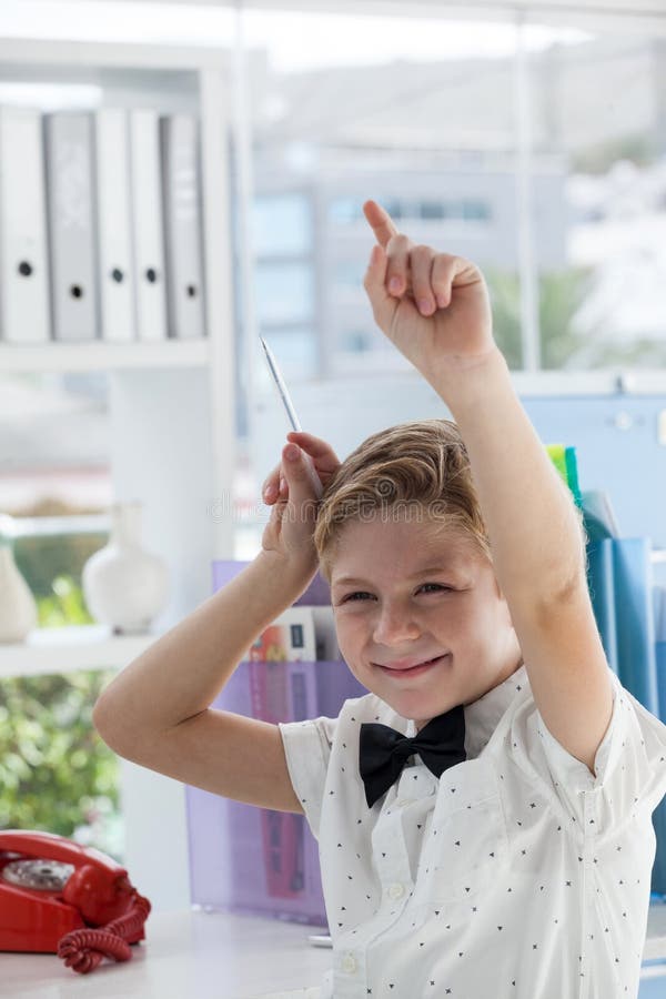 Smiling Businessman with Pen Pointing while Sitting at Desk Stock Photo ...