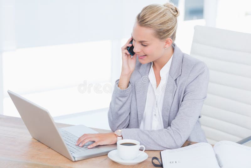 Smiling Businessman Phoning at Her Desk while Using Her Computer Stock ...