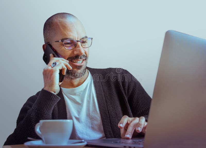 Smiling Businessman Talking on Cell Phone and Working on Computer Over ...