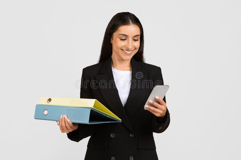 Smiling Businesswoman Multitasking with Folders and Smartphone Stock ...