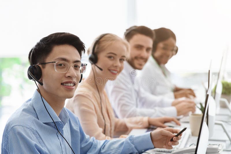 Smiling Call Center Workers Sitting in Row Near Their Computers at ...