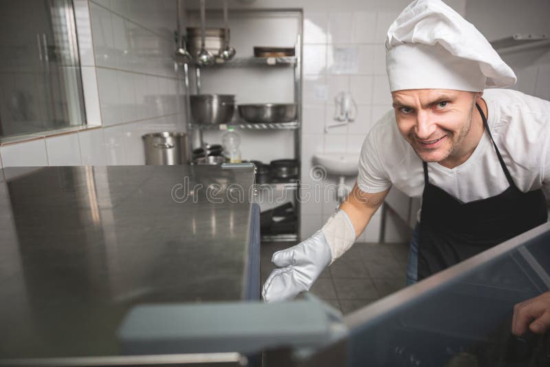Smiling chef opening oven stock image. Image of indoors - 83937985