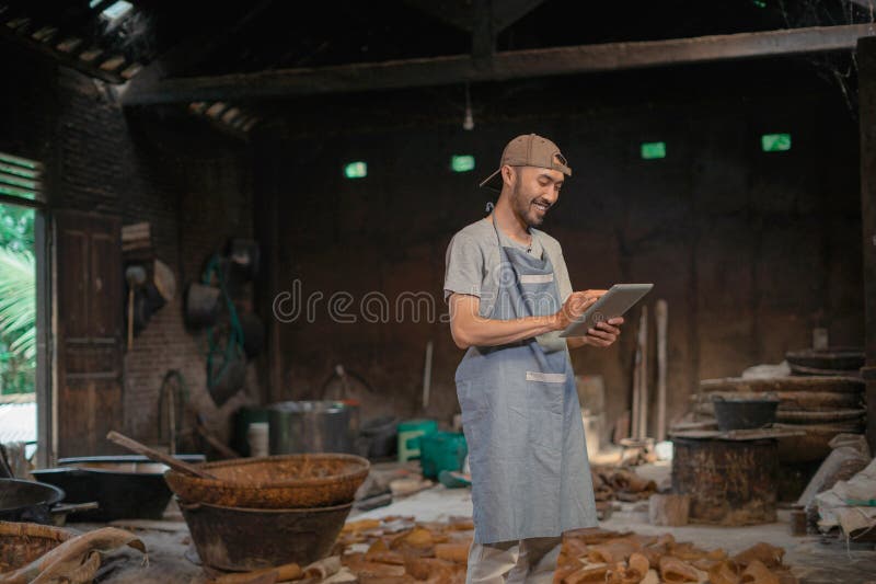 Smiling Chef in Rustic Kitchen Using Tablet for Recipe Management and ...