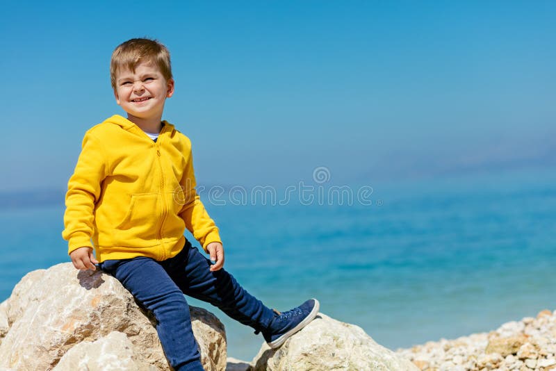 Smiling Child Sitting on a Rock with Seascape on the Background Stock ...