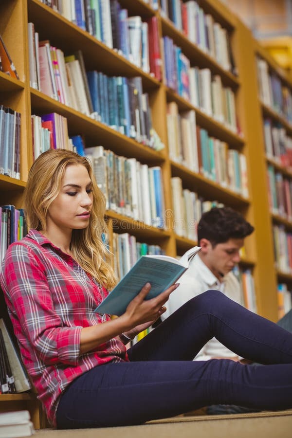 Smiling Classmates Reading Book while Leaning on Bookshelves Stock ...