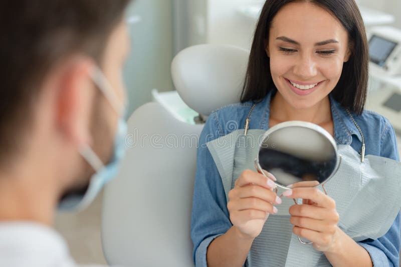 Smiling Client Sitting in Dental Chair and Looking in the Mirror on the ...