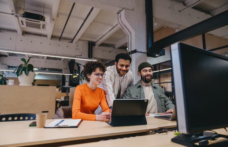 Smiling Colleagues Working Together in Office Using Laptop at Table ...