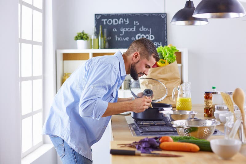 Smiling and Confident Chef Standing in a Large Kitchen Tasting a Cooked ...