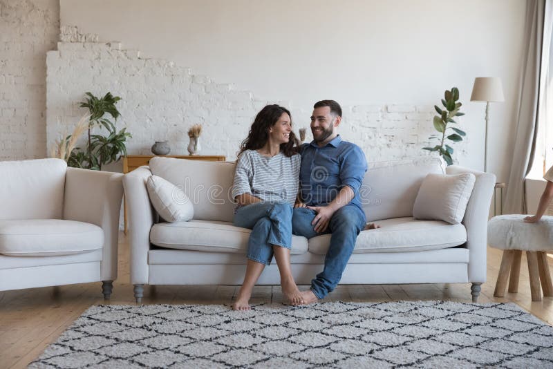 Smiling Couple Sit On Sofa Enjoy Pleasant Talk At Home Stock Image