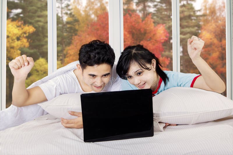 Smiling Couple Using Laptop on Bedroom Stock Photo - Image of internet ...