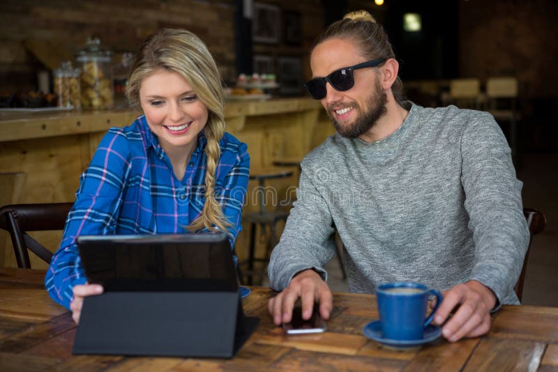 Smiling Couple Using Tablet Computer at Table in Cafeteria Stock Image ...