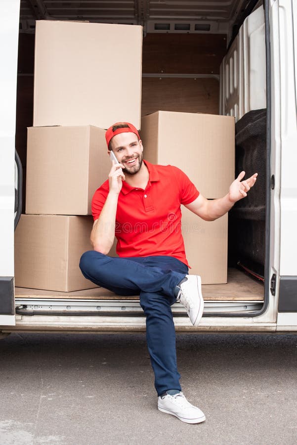Smiling Delivery Man in Red Uniform Talking on Smartphone while Resting ...
