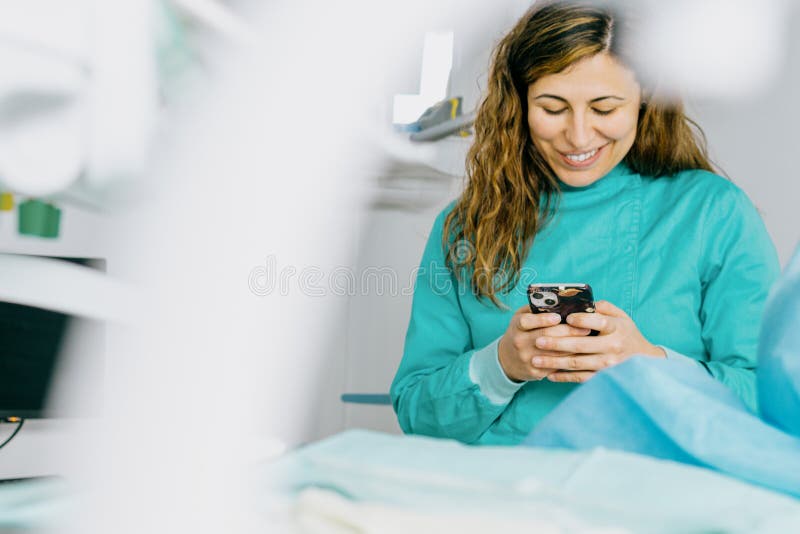 Smiling Dentist in the Operating Room Uses Mobile Phone Stock Photo ...