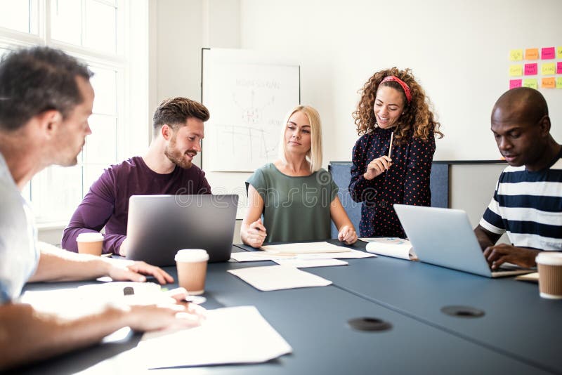 Smiling Designers Working on a Project Around an Office Table Stock ...