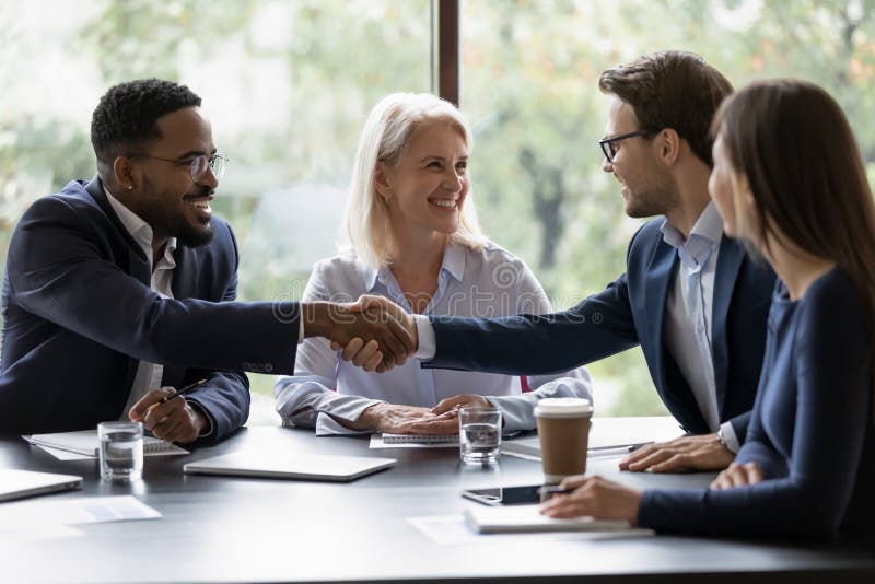 Smiling Diverse Employees Handshake at Briefing in Office Stock Photo ... Smiling Diverse Employees Handshake at Briefing in Office Stock Photo ...
